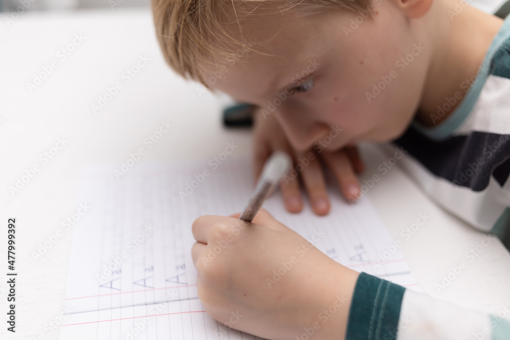 School boy practicing writing the alphabet at home. Boy child kid ...