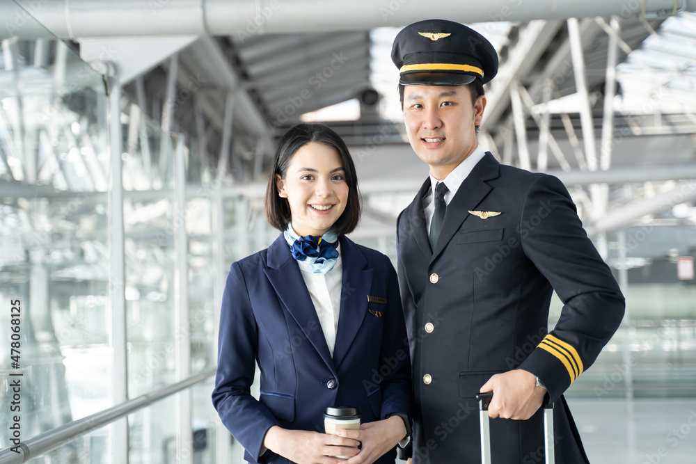 Asian airliner pilot and air hostess walk together in airport terminal ...
