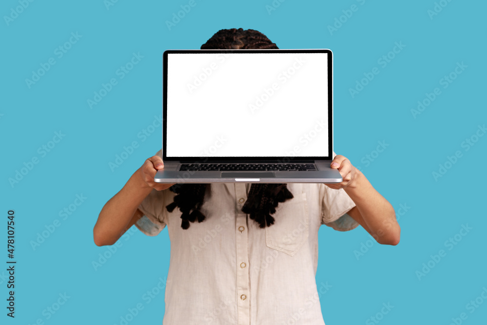 Portrait of unrecognizable woman hiding her face behind laptop with ...
