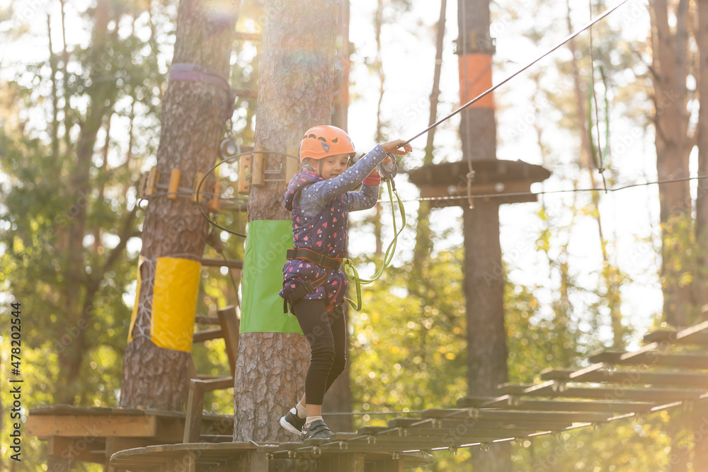 Little girl is standing on a rope, holding a rope with his hands. A ...