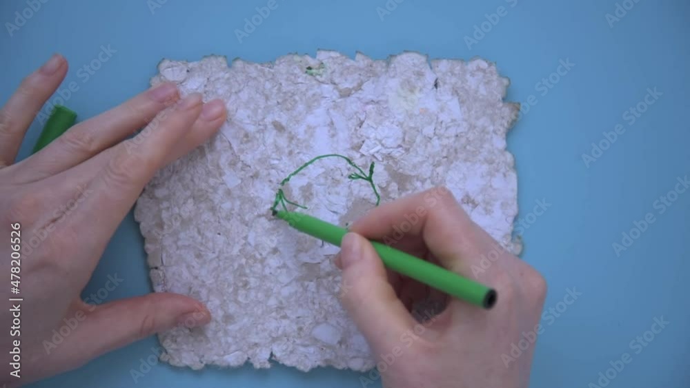 Women's hands draw a sign of reuse with a green felt-tip pen. Drawing ...