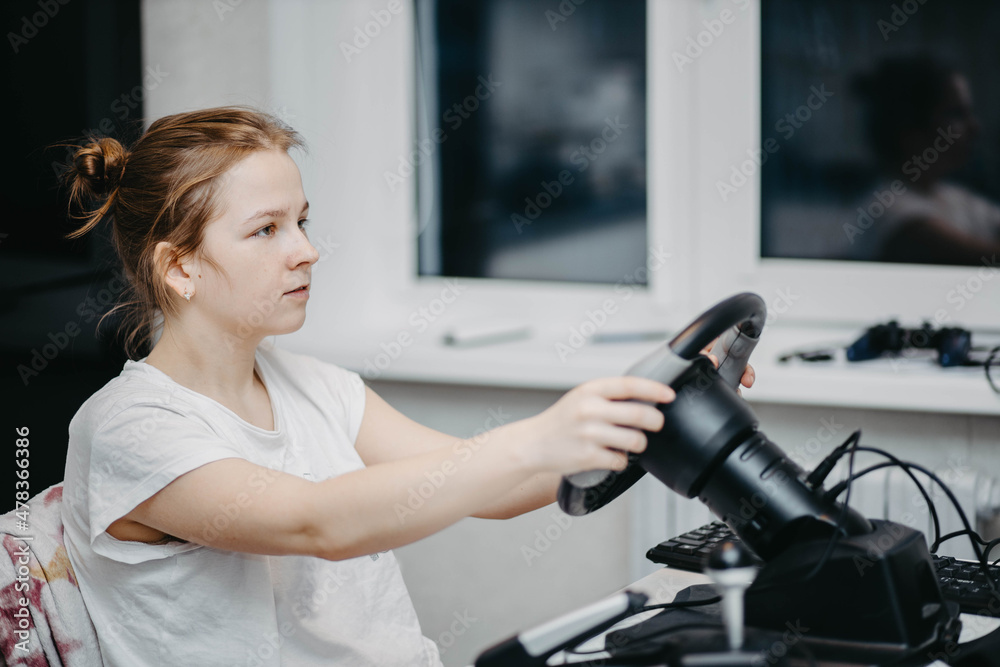 girl gamer playing a driving simulator with gamepads, steering wheel ...
