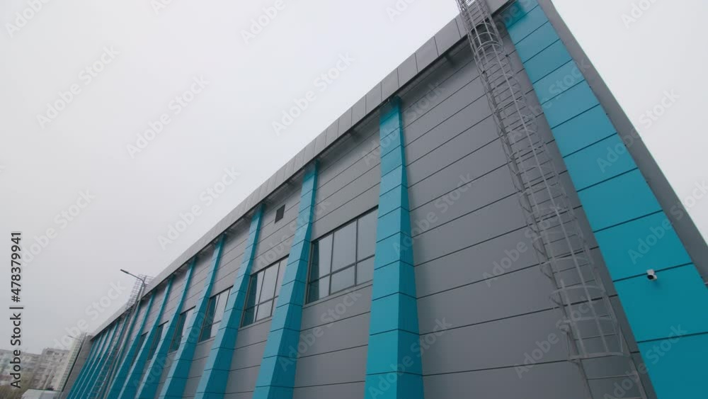 Grey and blue modern sports complex building with emergency fire ladder ...