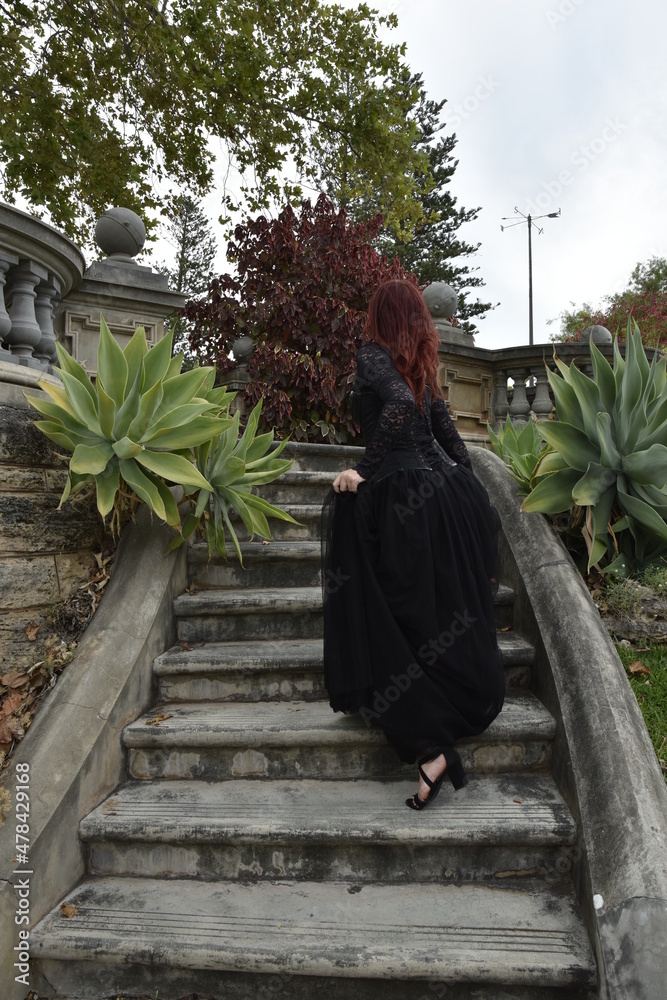 portrait of pretty female model with red hair wearing glamorous gothic ...