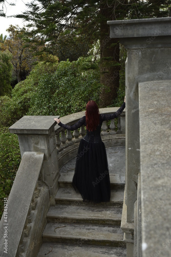 portrait of pretty female model with red hair wearing glamorous gothic ...