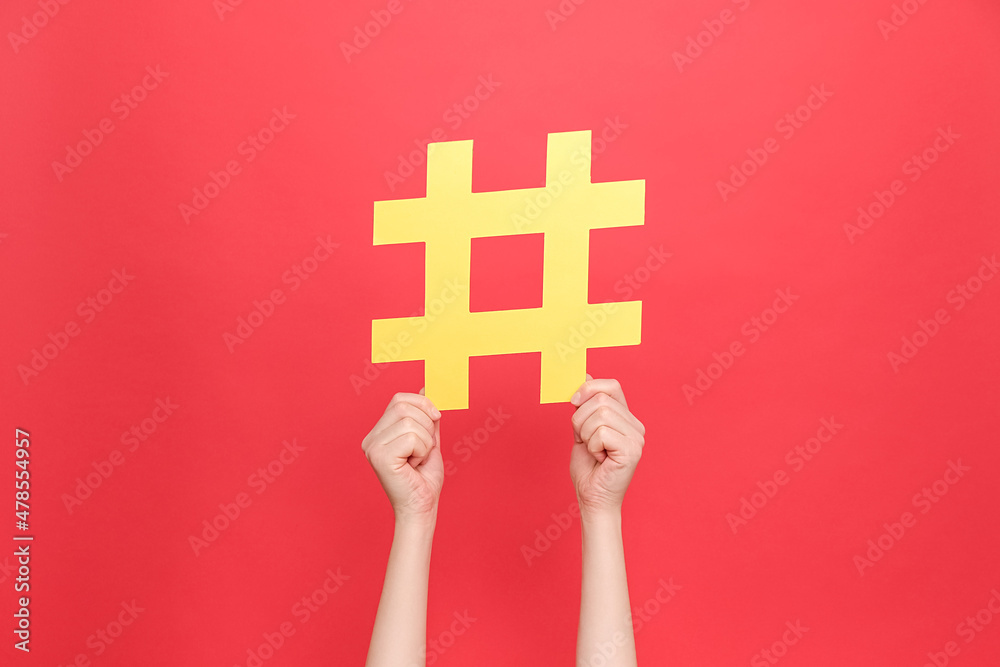 Close up of female hands holding large yellow paper hashtag symbol ...