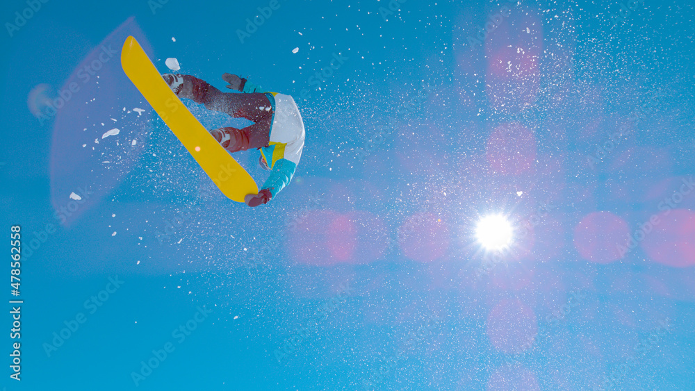 LENS FLARE: Athletic male tourist snowboarding in Alps does a spinning ...