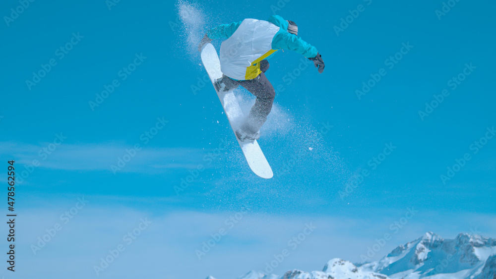 Male snowboarder flies through the air and does a spinning nose grab ...