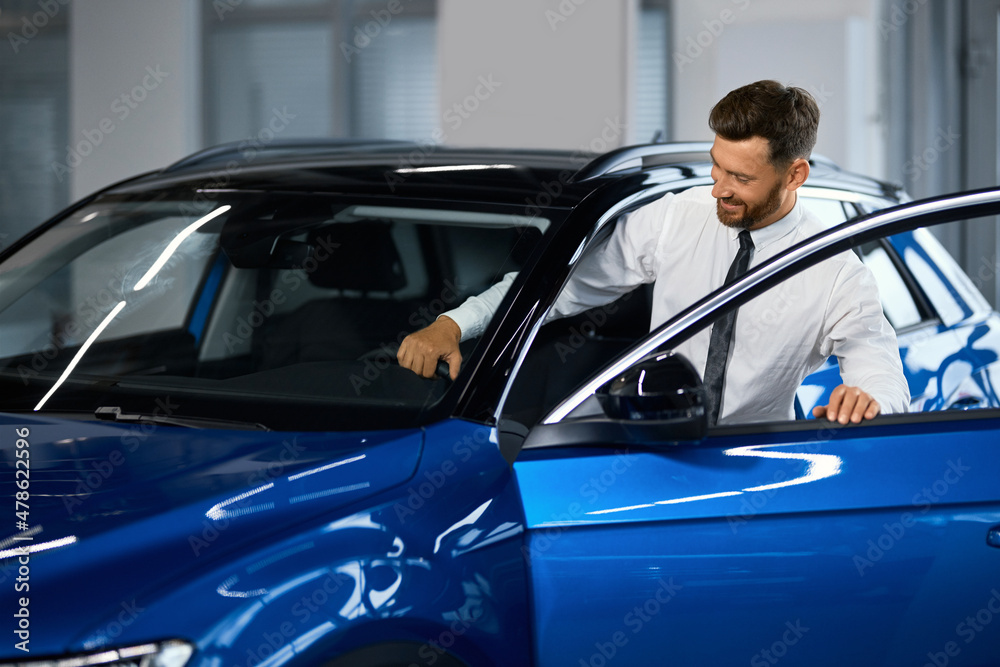 Happy caucasian man in formal wear getting inside luxury modern car for ...
