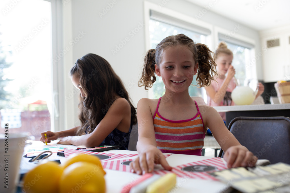 Girls making lemonade stand signs at dining table Stock Photo | Adobe Stock