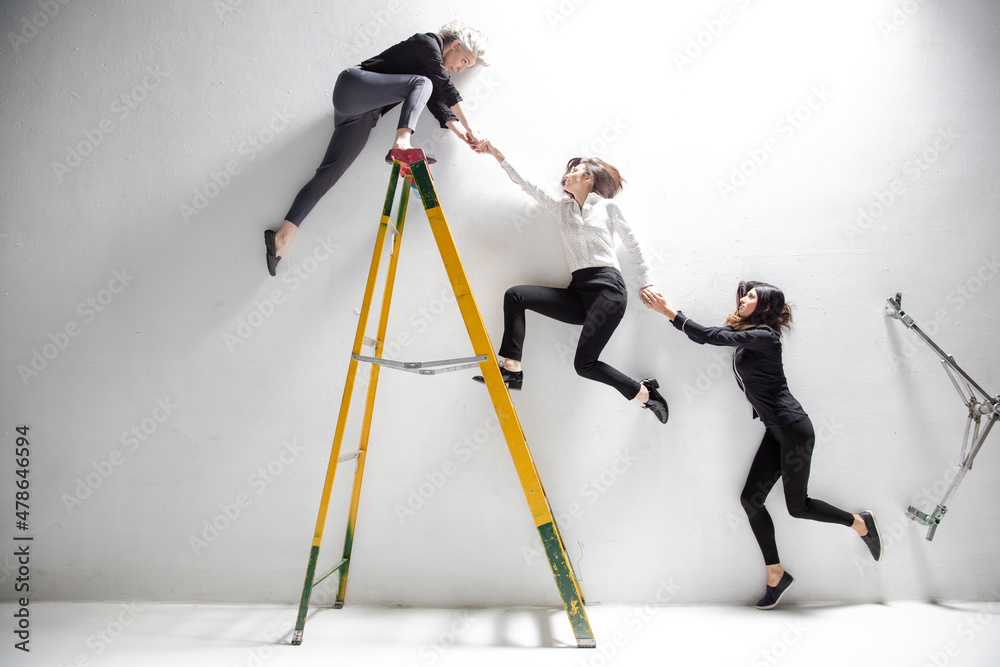 Businesswomen holding hands, helping lift each other on ladder Stock ...