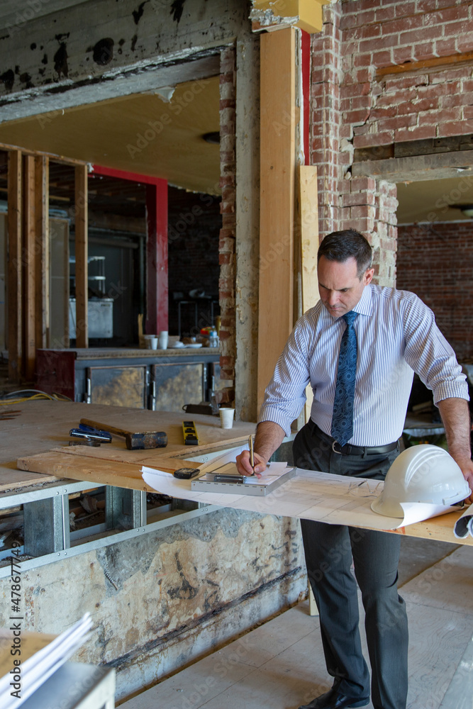 Male architect writing notes on work order at construction site Stock ...