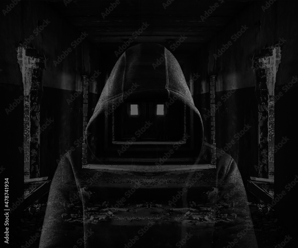 anonymous man in the dark hood standing in the abandoned corridor. no ...