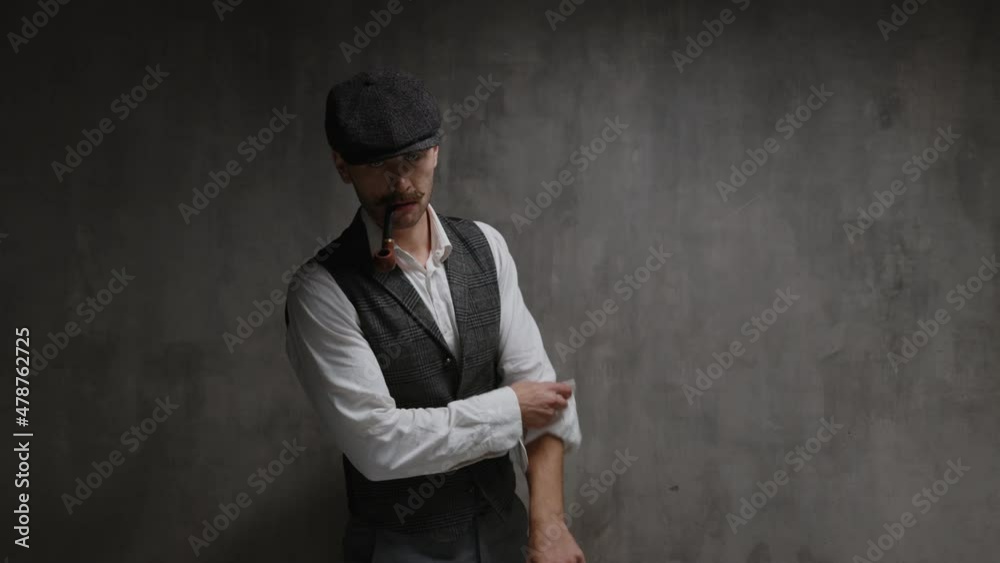 Young dangerous gangster man dressed in vintage suit, cap and with ...