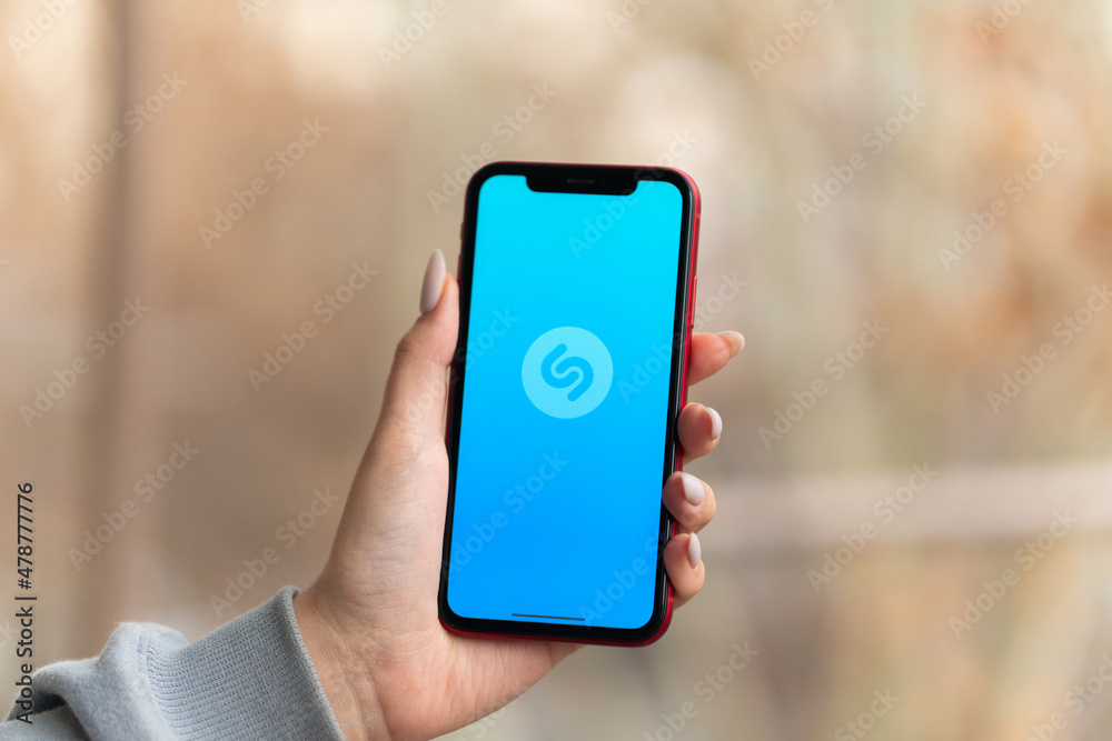 Hands holding smartphone displaying logo of Shazam, an American ...