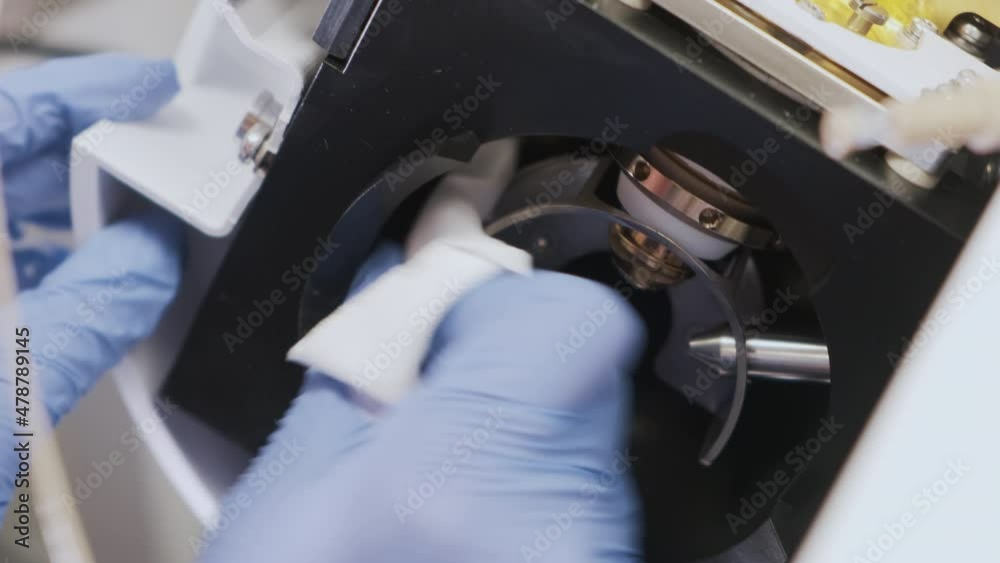 Close up scientist cleaning an ion source of mass spectrometer with ...