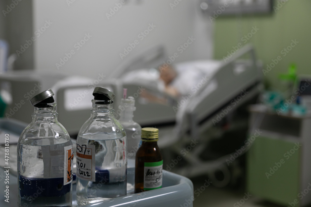 Glass bottles on a medical solution stand on the medical table in focus ...