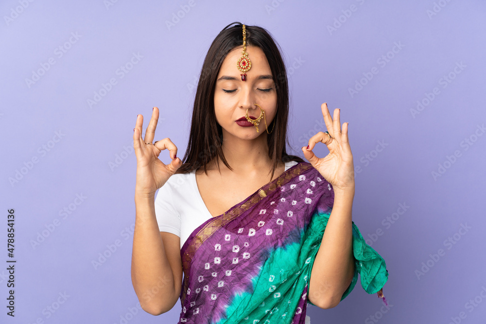 Young Indian woman isolated on purple background in zen pose Stock ...