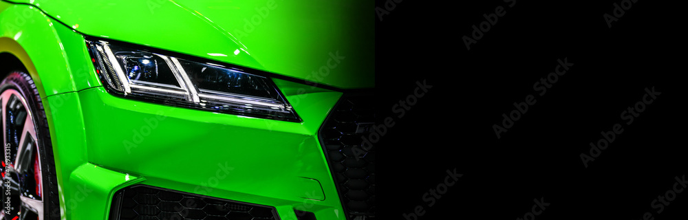 Front view of the LED headlights modern green car on black background ...
