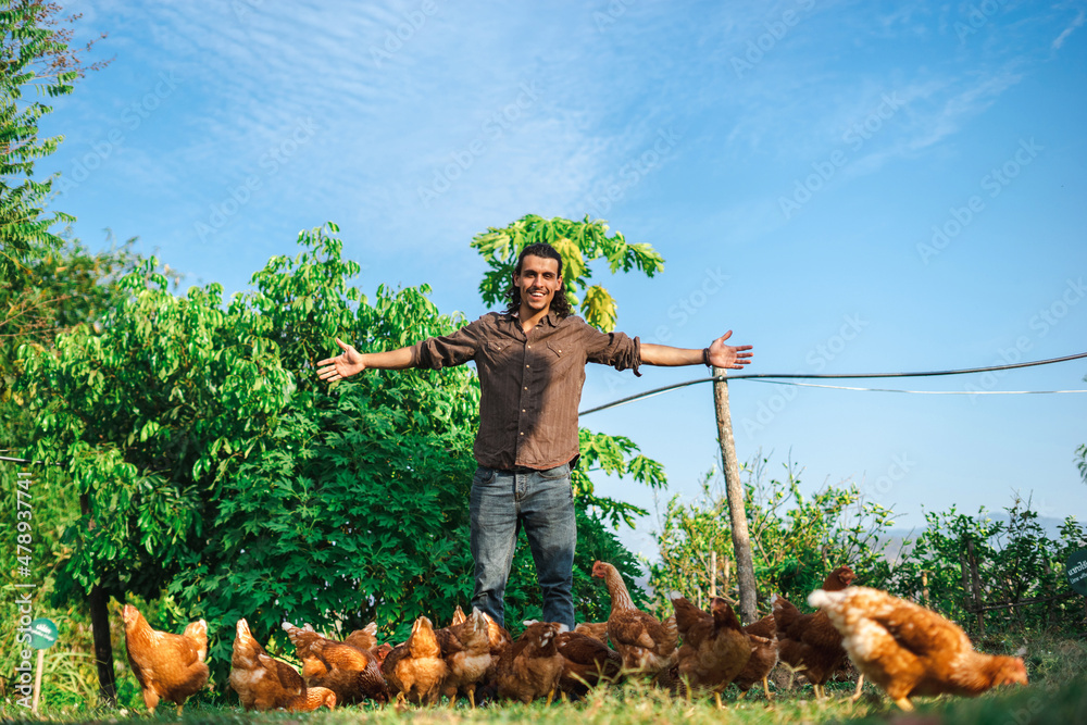 Portrait of a cheerful farmer taking care flock of chicken outdoor. A ...