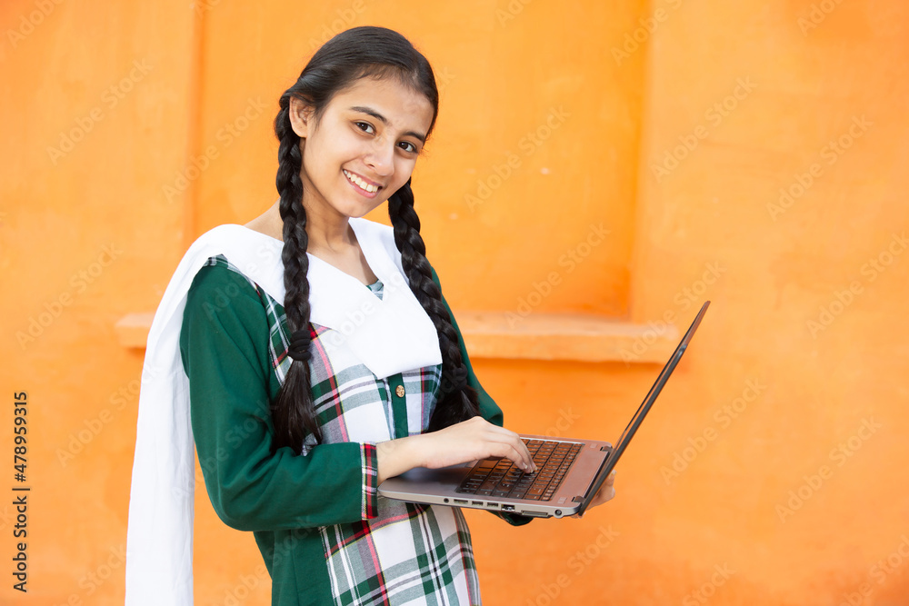 Portrait of Happy young indian school girl using laptop. Smiling ...