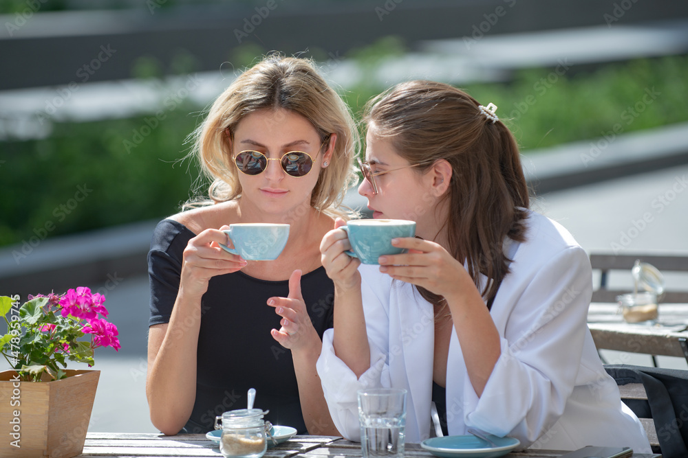 Girl friends in cafe outdoor. Outdoors portrait of two young beautiful ...