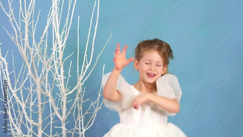beautiful little girl is dancing and smiling in white fluffy dress on ...