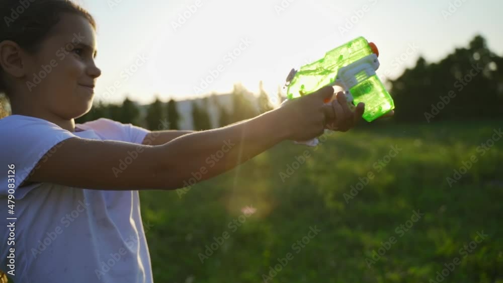 Close-up Kid shoots and sprays from a water pistol. Slow motion teenage ...