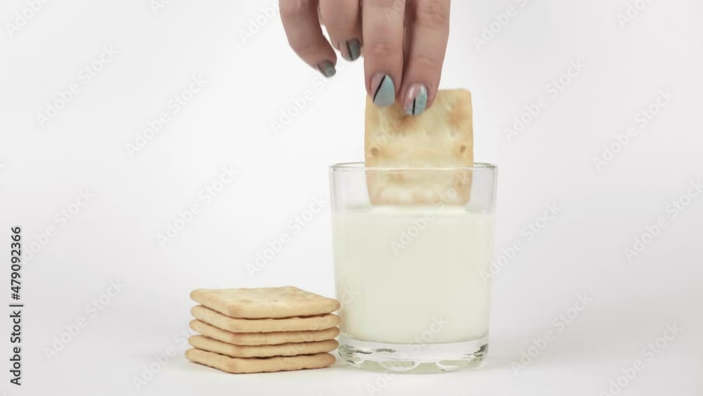 A woman's hand drops a cookie into the milk. Cookies and milk on a ...