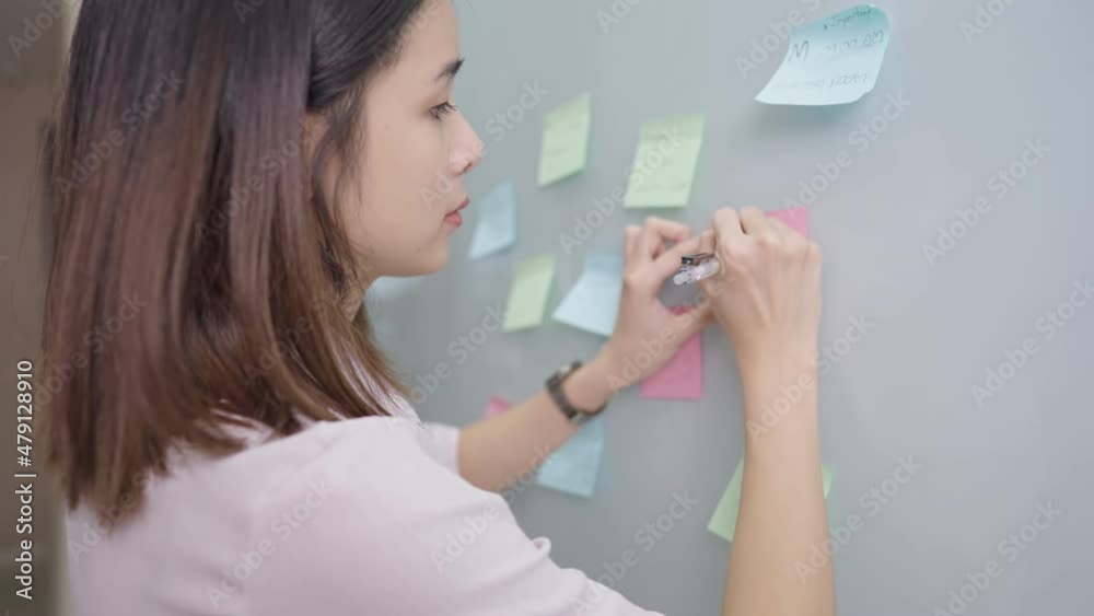 Young asian working woman writing company meeting criteria on the note ...