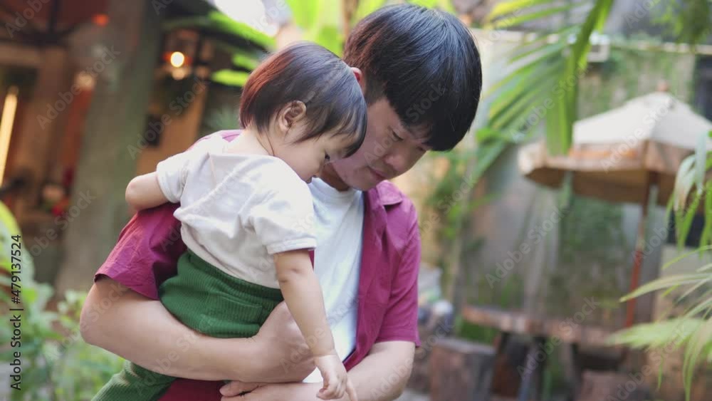 Young asian daddy carrying his baby girl standing outside, with natural ...
