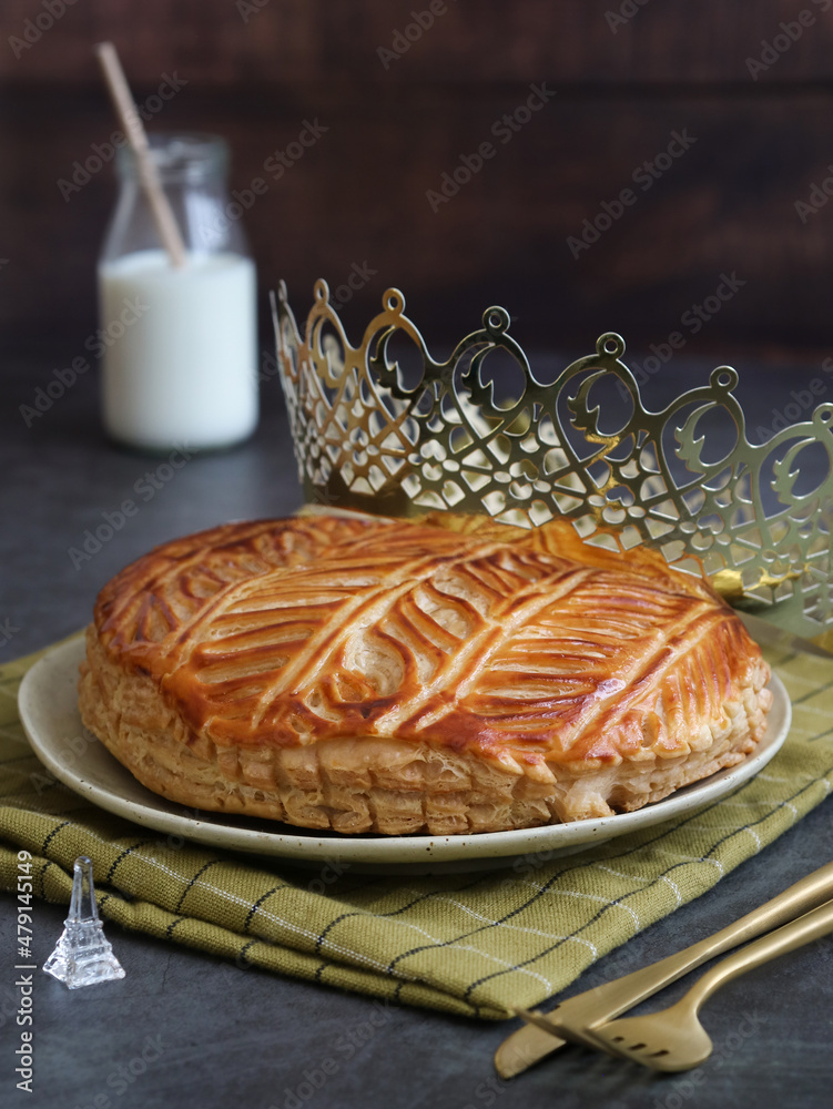 A traditional French galette des rois or king cake on a plate with ...