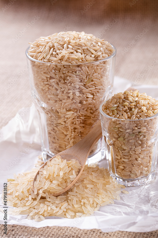Copos cheios de arroz integral e arroz agulha e colher de bambu com ...