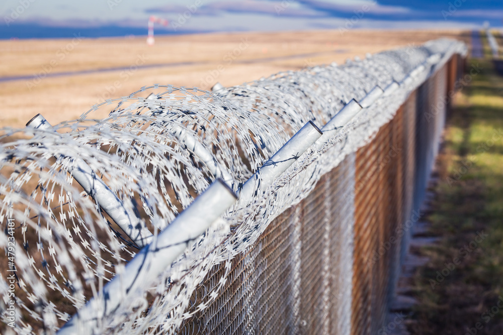 High fence obstacle with rolls of razor blade barb wire on top Stock ...