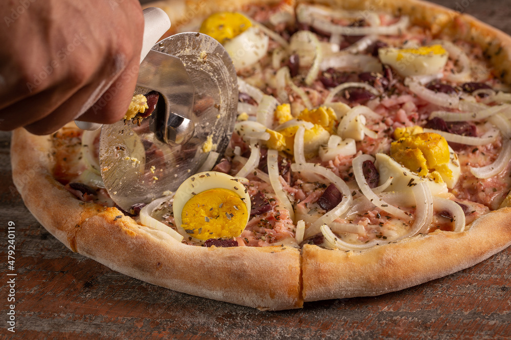 Portuguese Pizza slice being cut. Pizza Portuguesa is a Brazilian pizza ...