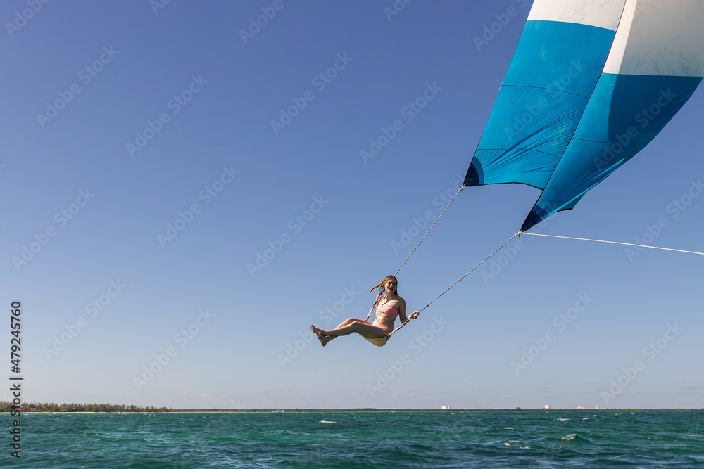 Foto de Girl flying over the Caribbean sea during fun activity with a ...