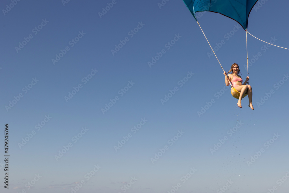 Girl flying over the Caribbean sea during fun activity with a spinnaker ...