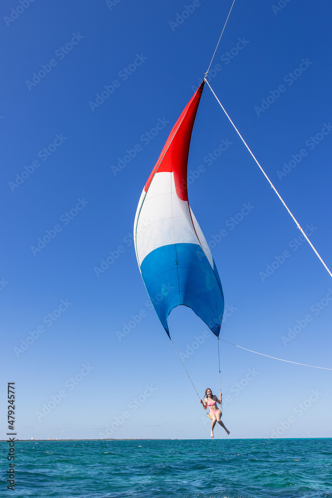 Girl flying over the Caribbean sea during fun activity with a spinnaker ...