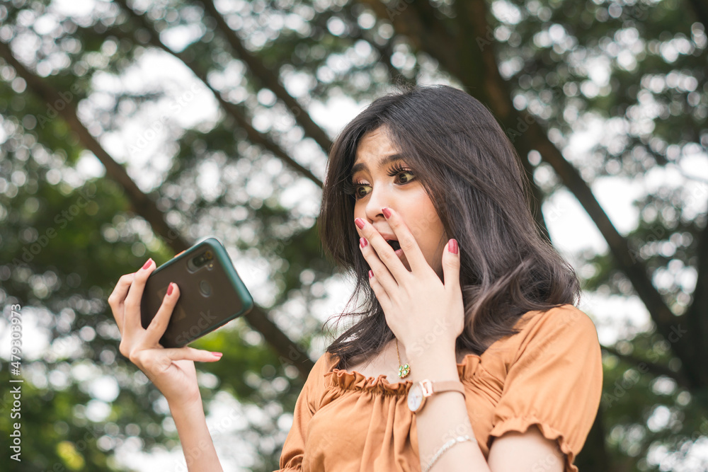 A shocked young woman aghast and her mouth wide open upon viewing a ...