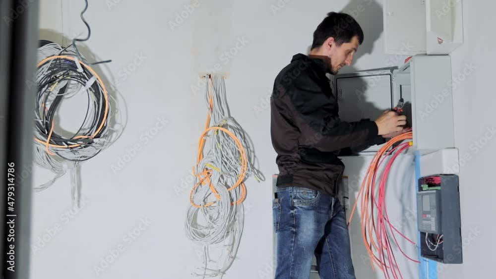 An electrical engineer connects an electrical switchboard in a new home ...
