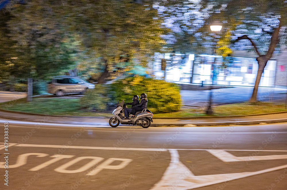 Panning of a scooter type motorcycle with 2 passengers at night Stock Photo | Adobe Stock