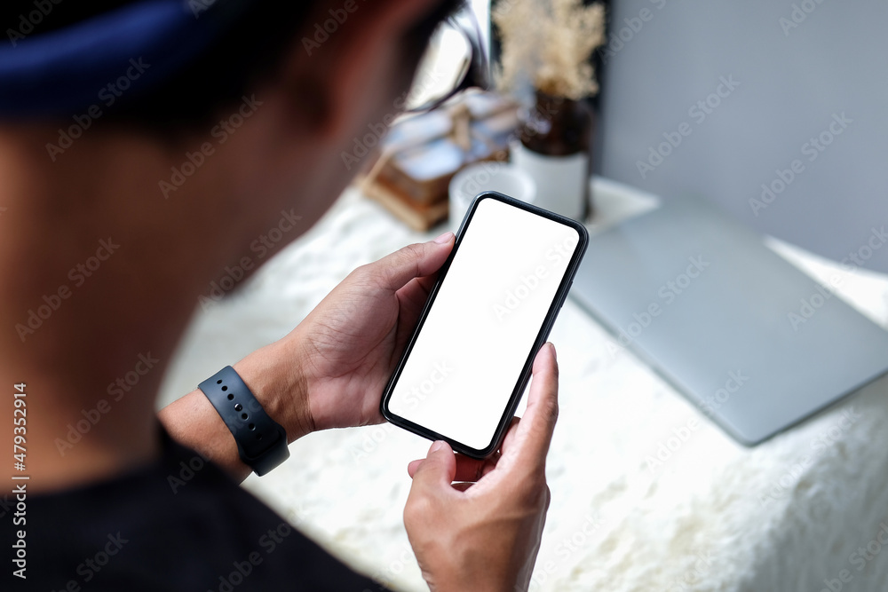 Over shoulder view of young man holding smart phone with blank screen. Stock 写真 | Adobe Stock