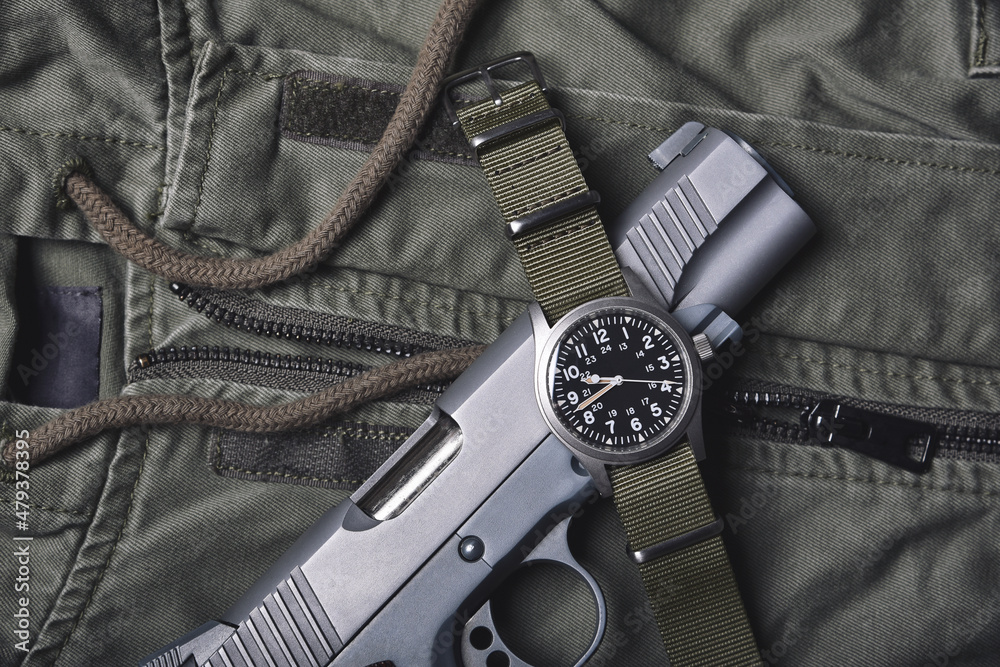 Vintage military watch and pistol on army jacket green background ...