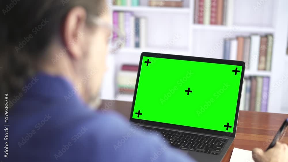 Over the shoulder shot of a man working looking at green screen. Office ...