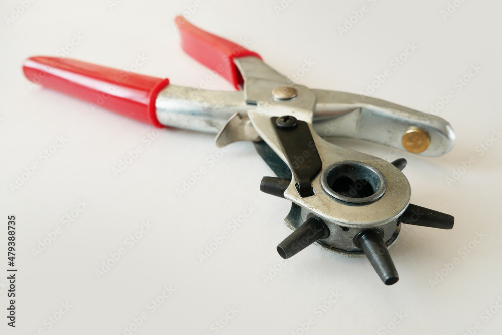 Puncture holes in the strap using a punch isolated on white background ...