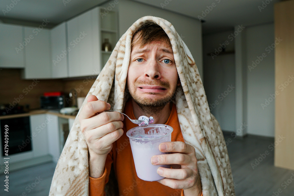 Portrait of heartbroken young man eating ice cream from bucket. Sad guy ...