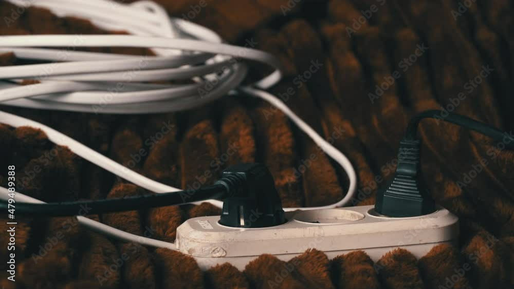 A woman's hand pulls a plug from a white extension cord. The wires are sticking out. Danger ...
