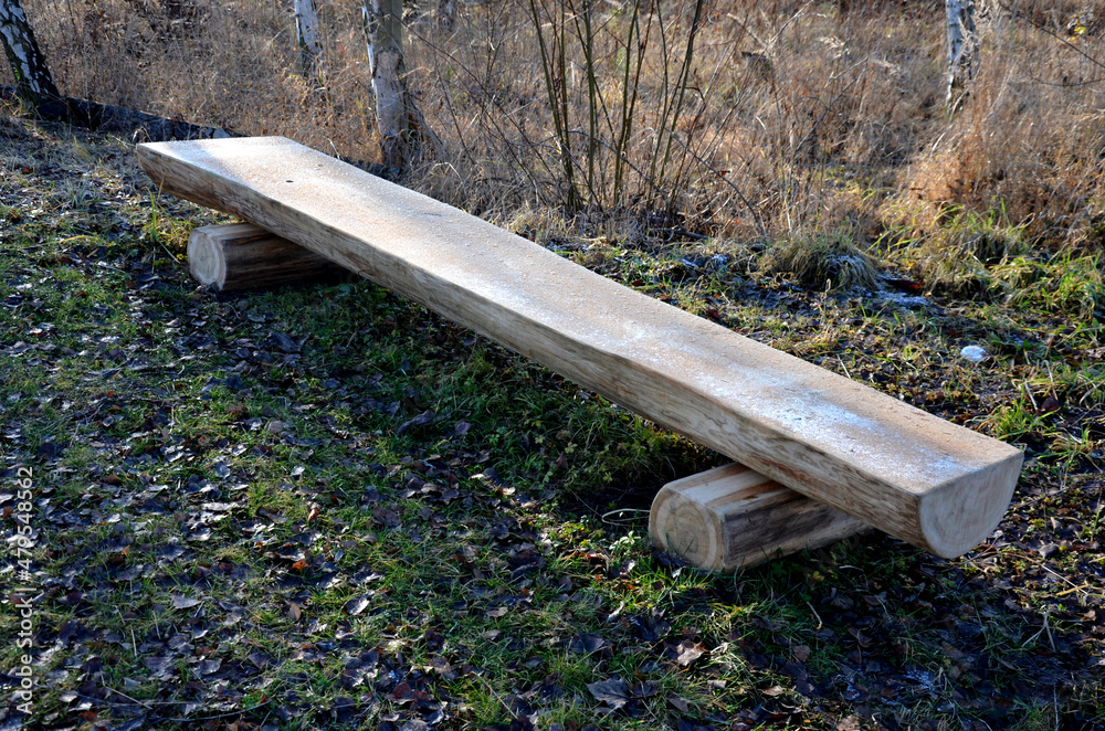 rustic bench made of halved debarked logs with legs made of logs ...