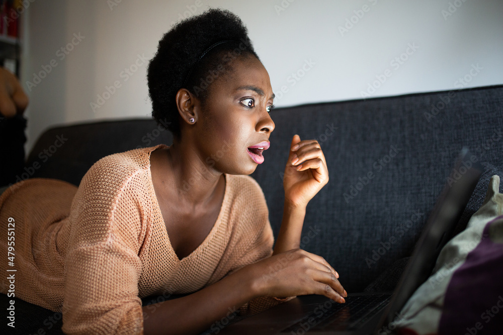 shocked black woman watching video on laptop Stock Photo | Adobe Stock