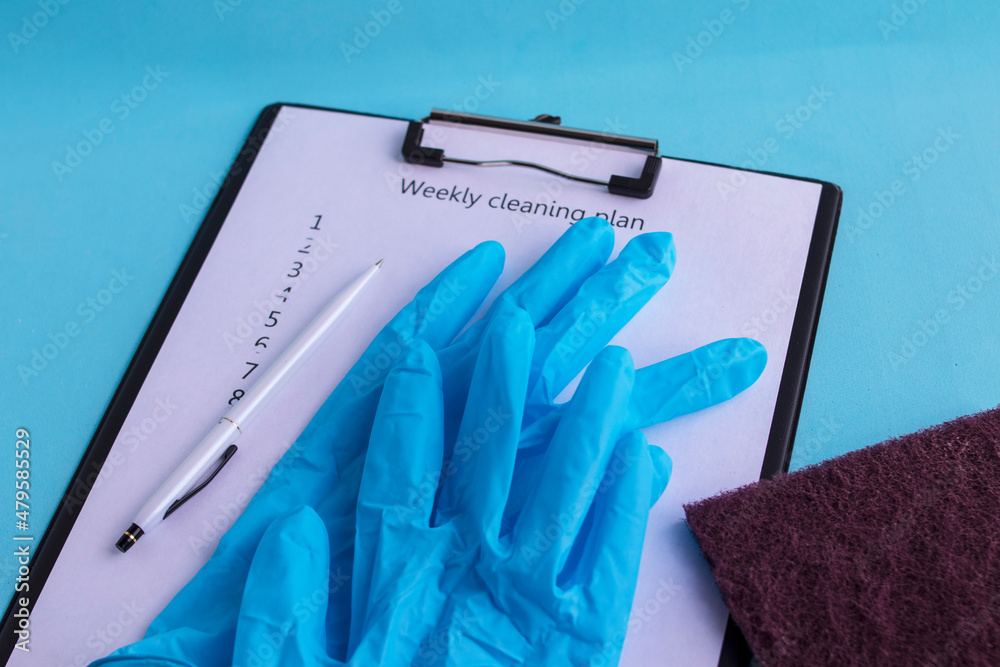 Weekly cleaning plan with pen on clipboard and rubber cleaning gloves ...
